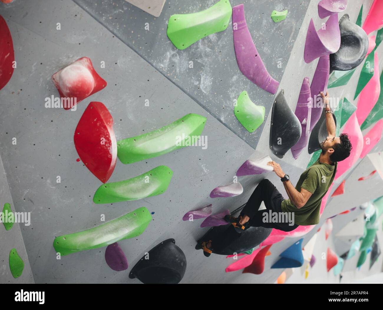 Dramatic action shot looking down on man climbing wall at indoor ...