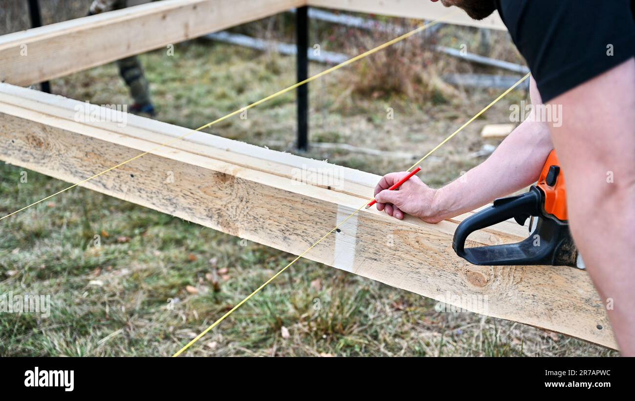 Man worker building wooden frame house on pile foundation. Close up ...