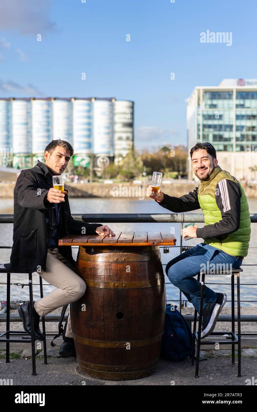 Two friends drinking and toasting with beer at pub brewery. They are ...