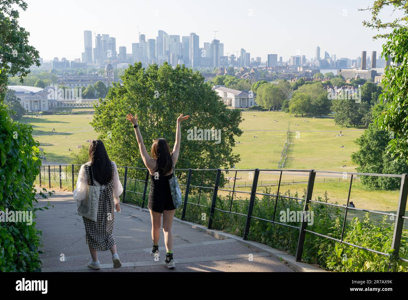 London UK. 13th June 2023. Two women embrace the sunshine walking down ...