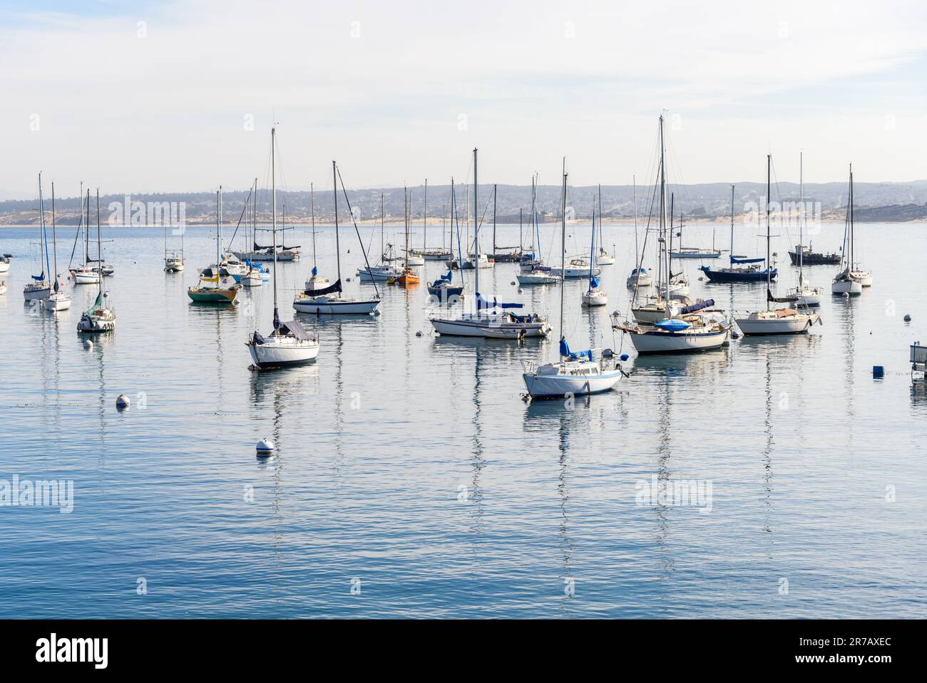Saling boats moored to buoys in a harbour on a misty autumn morning ...