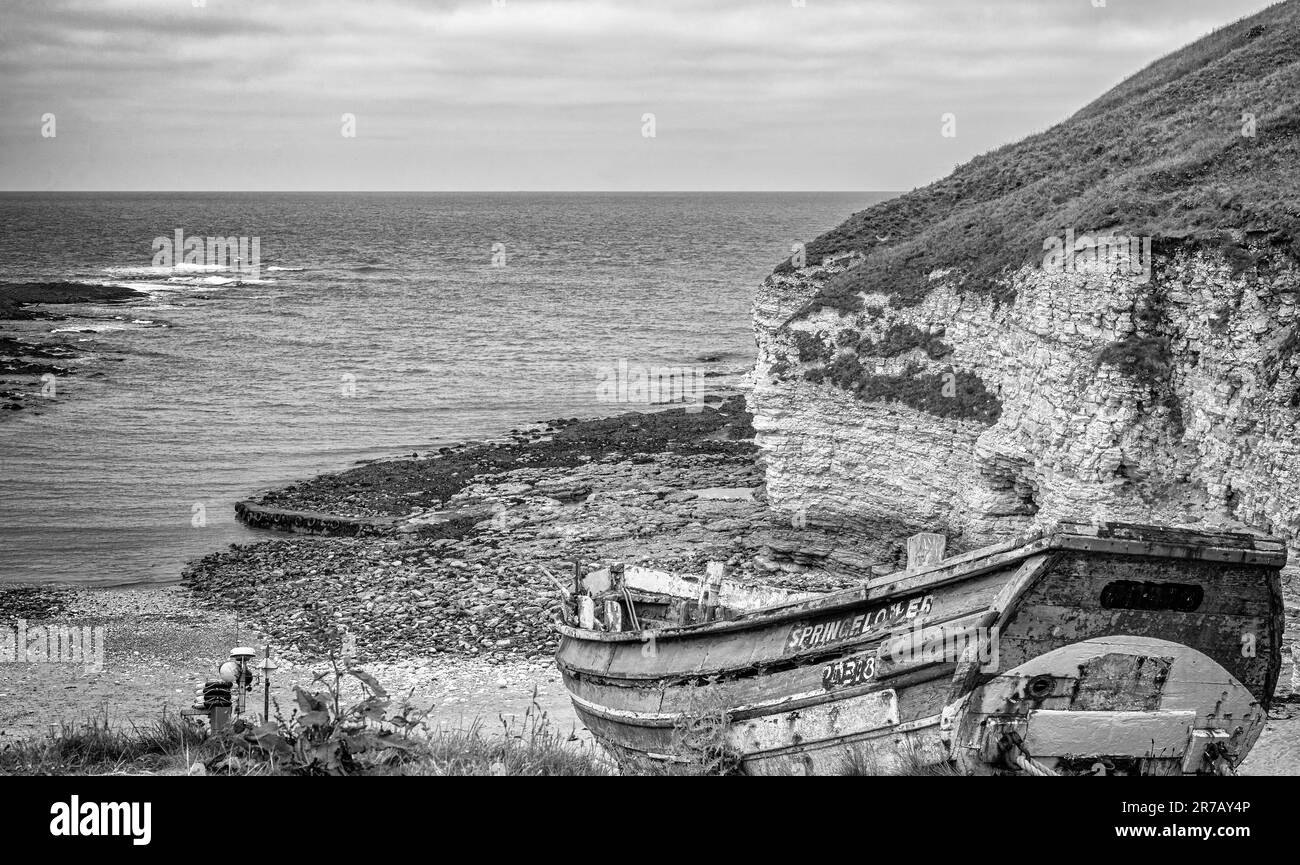 An old boat is the foreground pointing downwards to a beach with chalk ...