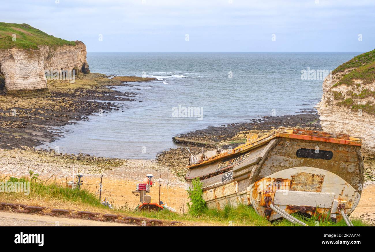 An old boat is the foreground pointing downwards to a beach with chalk ...