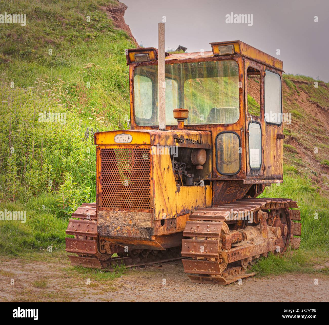 A plant vehicle with caterpillar tracks stands at the foot of a cliff ...
