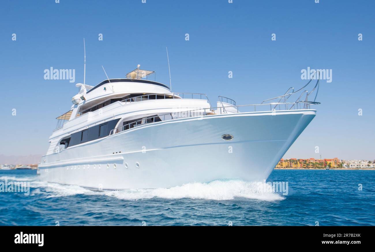 A luxury private motor yacht under way on tropical sea with bow wave ...