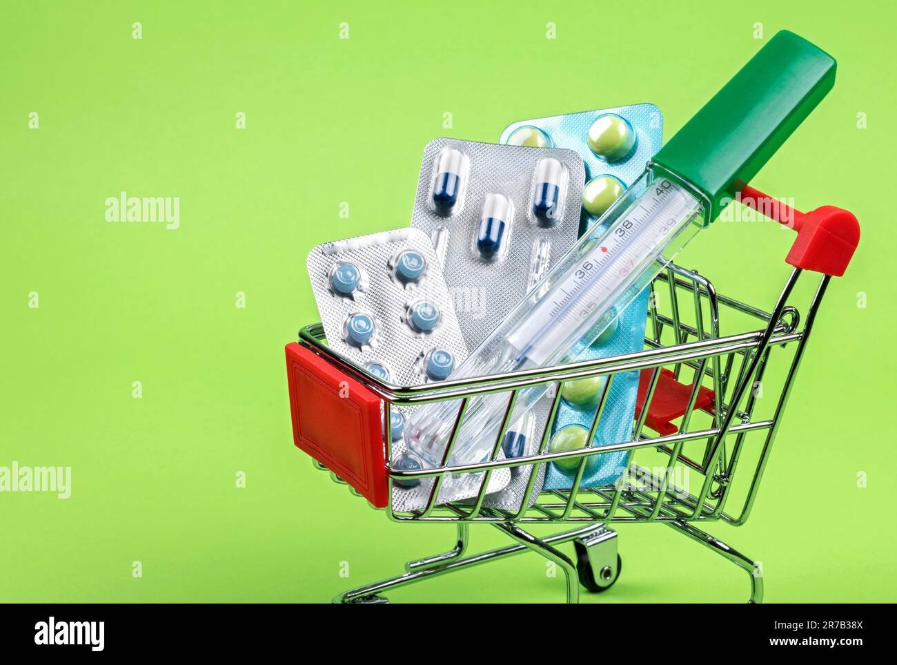 Thermometer, pills, tablets and vitamins in a shopping cart on green ...