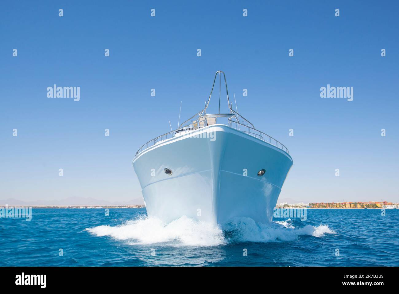 A luxury private motor yacht under way on tropical sea with bow wave ...