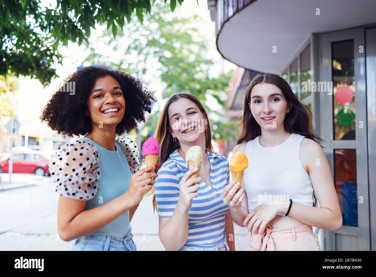 Three cheerful multiracial female teenager girls holding colorful ice ...