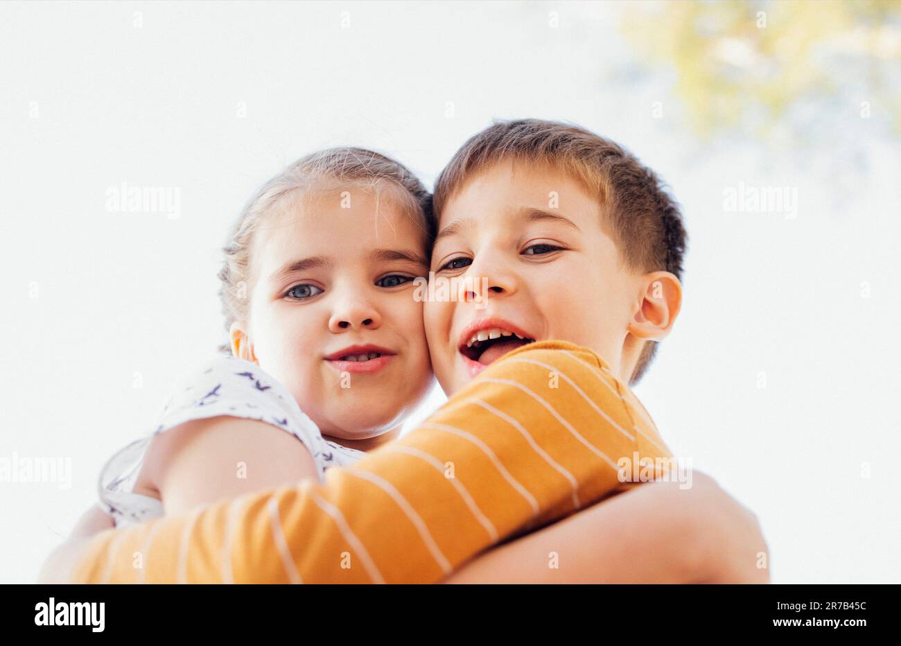 Little cute kids in casual clothes hug each other tightly. Pretty girl ...