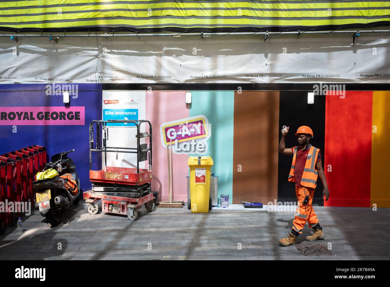 A construction site traffic marshall is seen below a large banner that ...