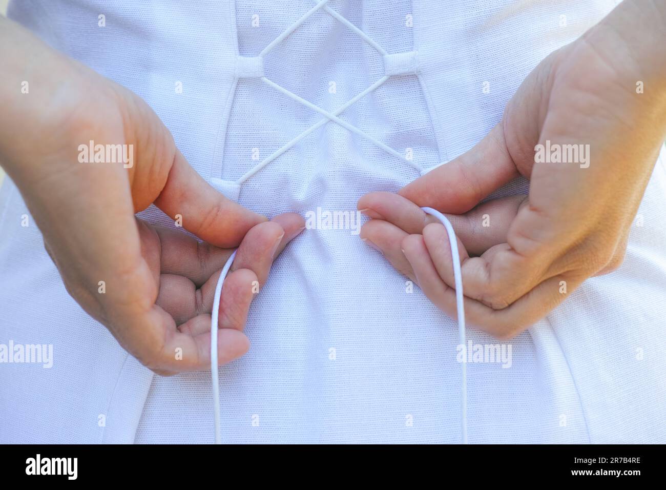 A woman tightening laces on the back of her dress Stock Photo - Alamy