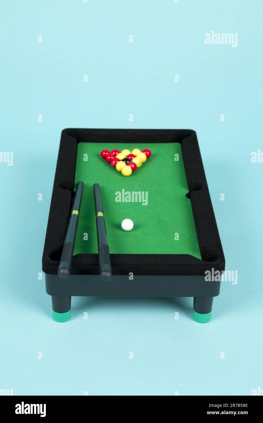 a miniature plastic billiard table on a turquoise background, complete ...