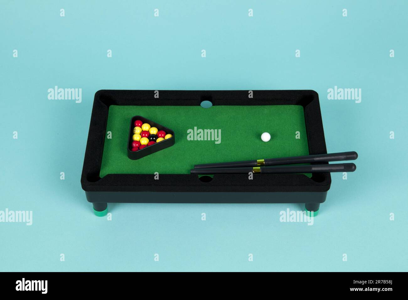 a miniature plastic billiard table on a turquoise background, complete ...