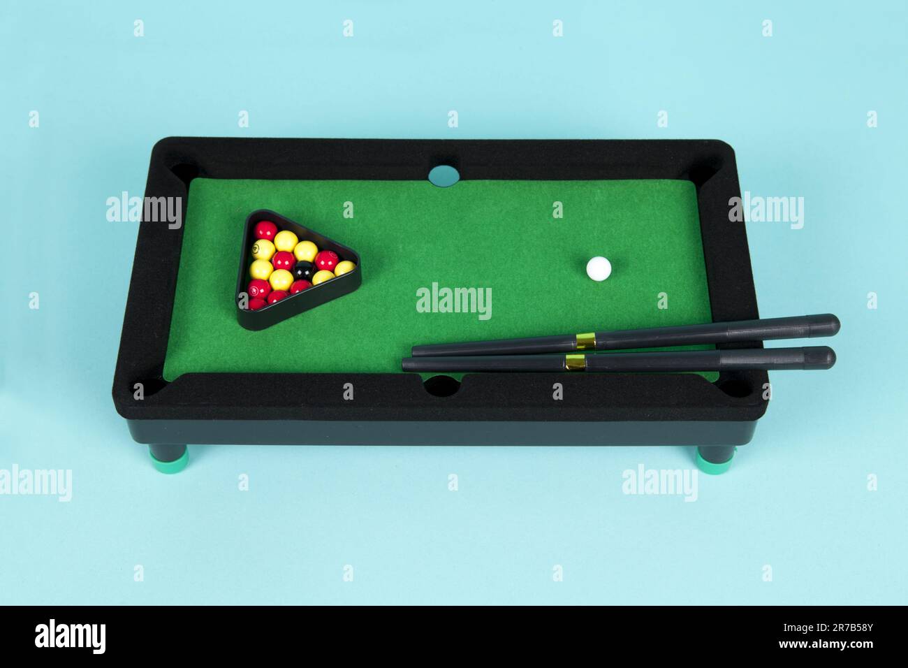 a miniature plastic billiard table on a turquoise background, complete ...