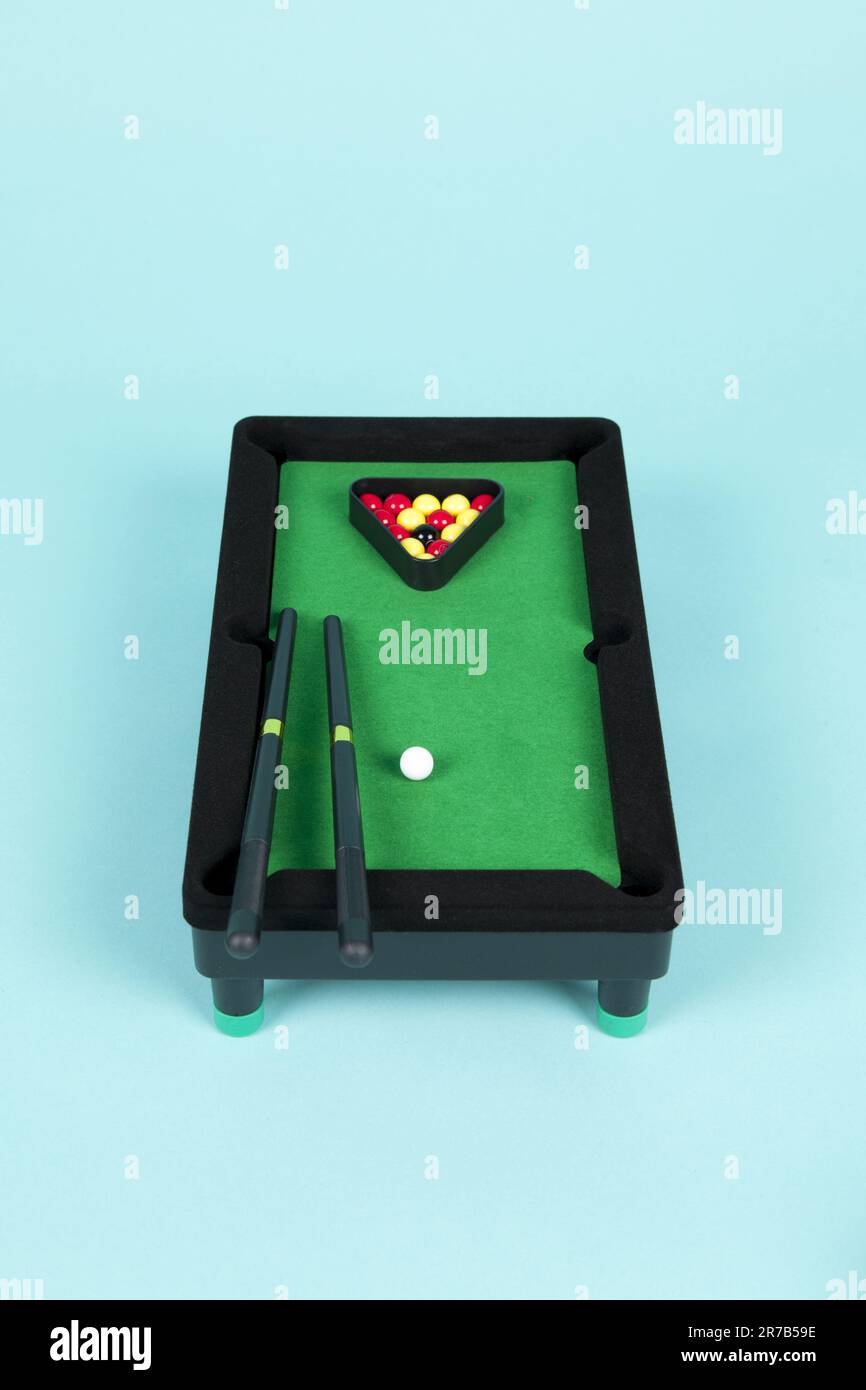 a miniature plastic billiard table on a turquoise background, complete ...