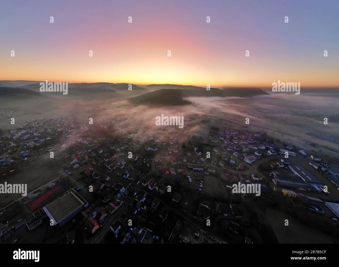 An aerial stunning view of a foggy sunset over Oberstenfeld, Germany ...