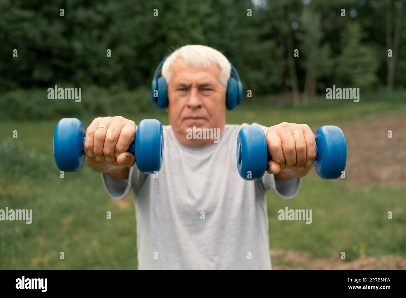 Senior man working out outdoors. Person lifting dumbbells. Old male ...