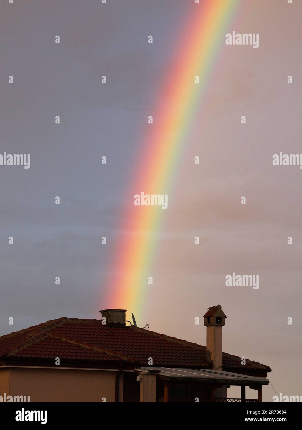 Multicolored rainbow in the sky after the rain over the roof of the ...