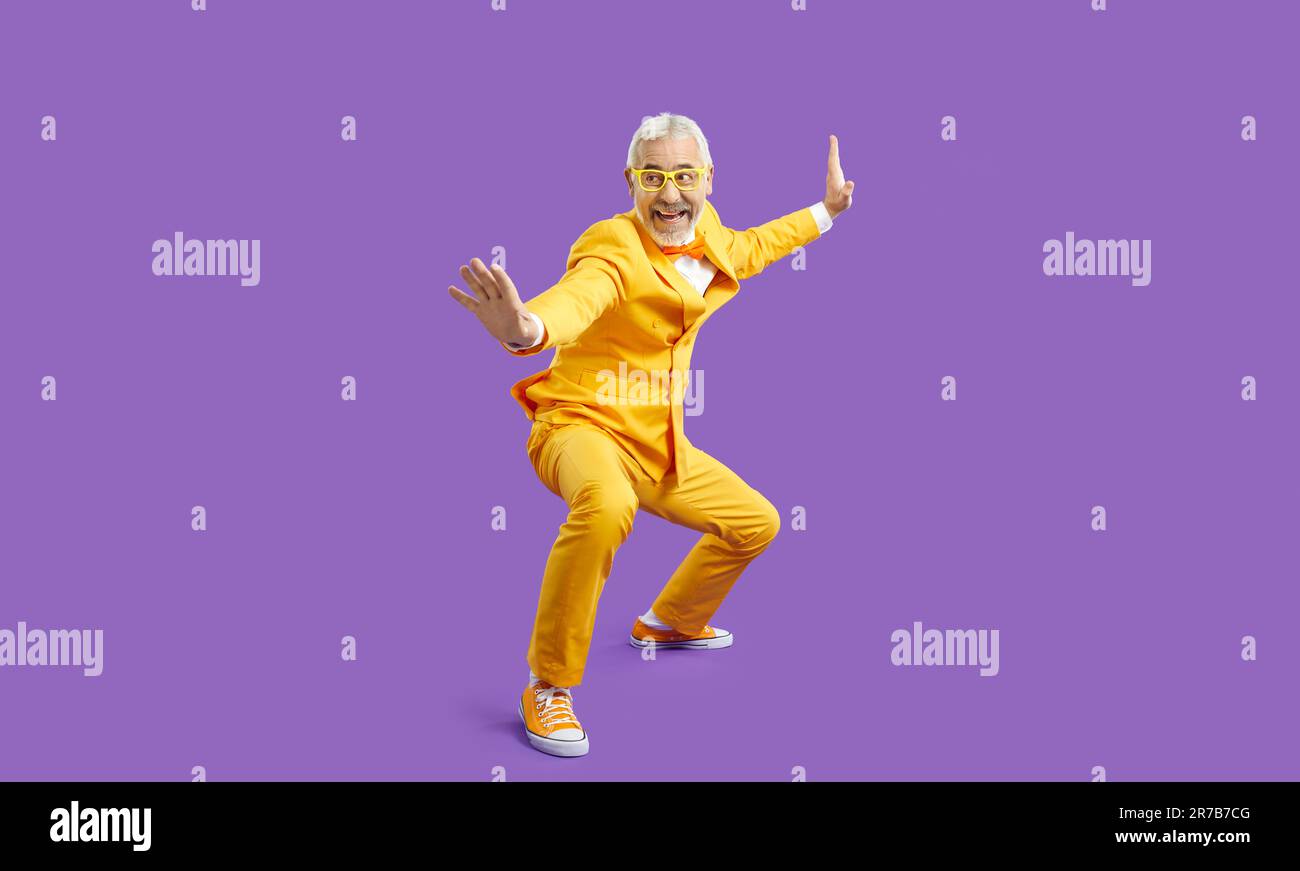 Funny happy senior man in yellow suit standing in kung fu fighting pose ...