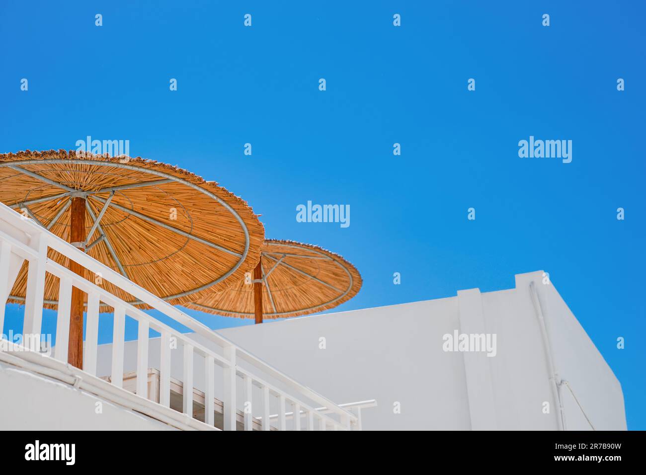 Sun umbrellas on the roof of the house against the blue sky, the Greek ...