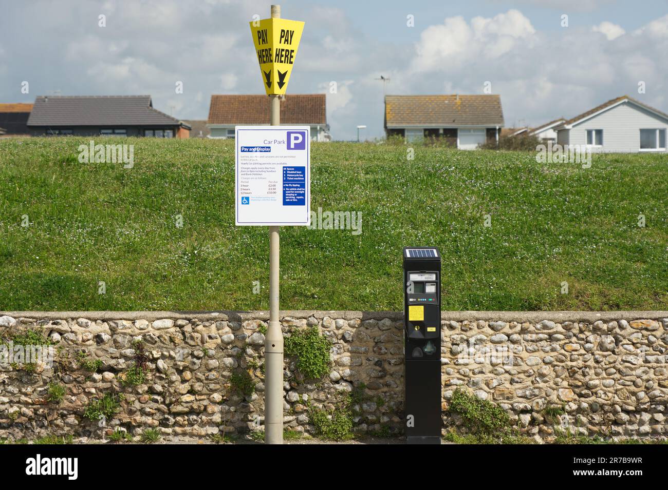Pay Here sign and machine for parking payment on seafront road. With ...