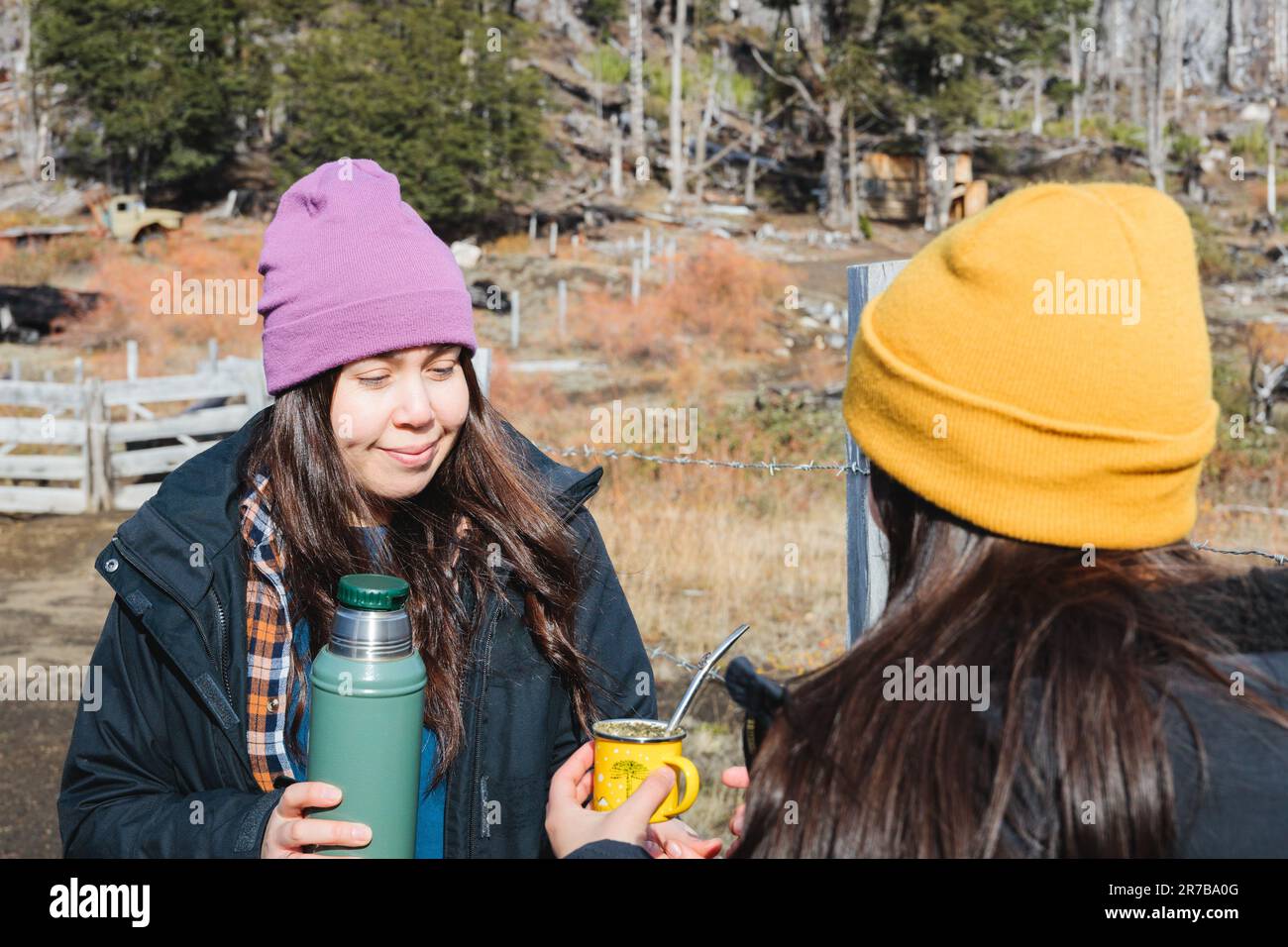 Couple of two young women in warm clothes, sharing and enjoying yerba ...