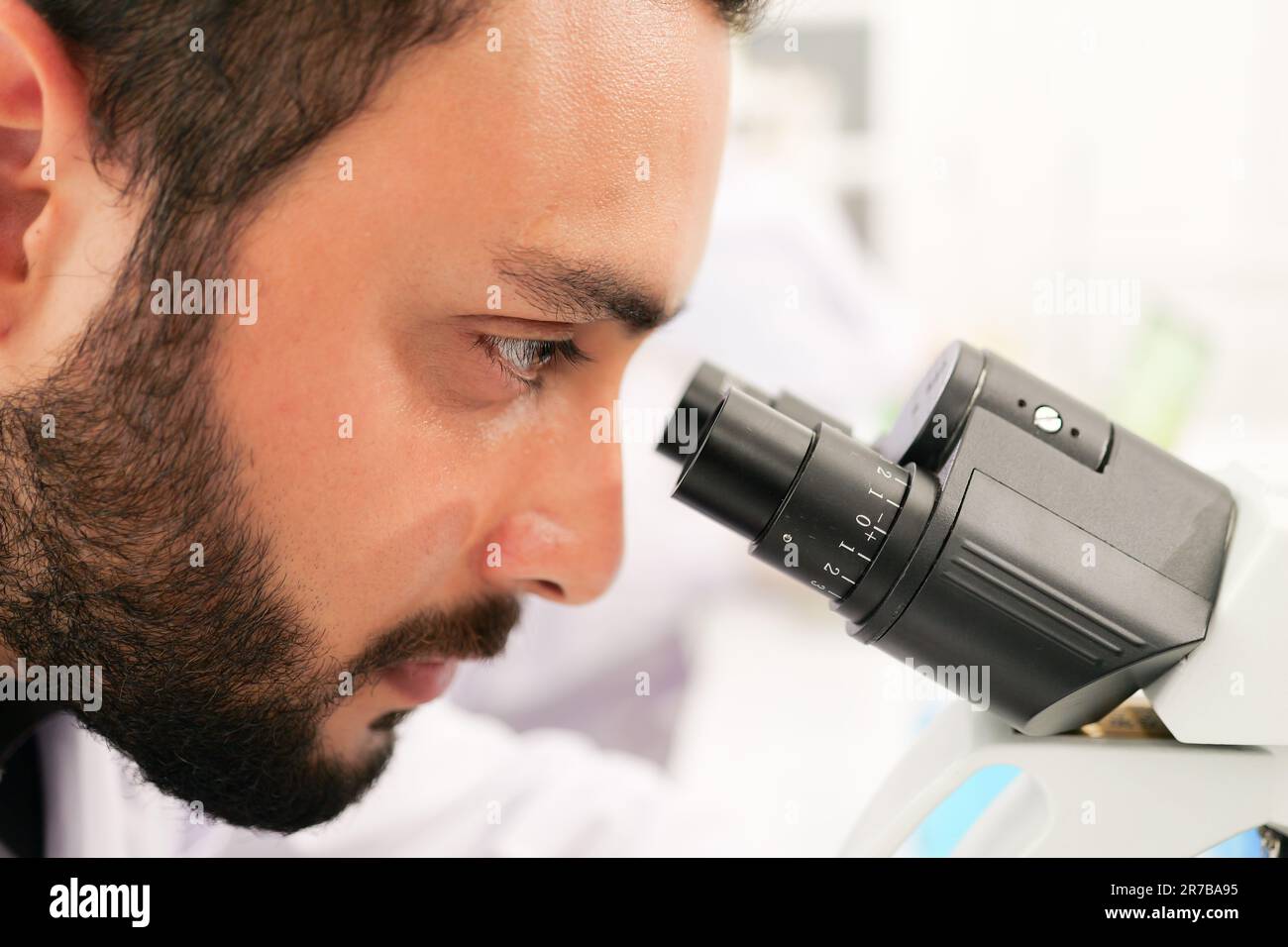 Professional male scientist looking through microscope in laboratory ...