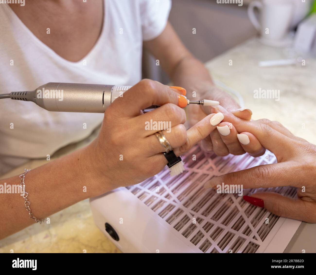 The nail technician prepares the client's nails for coating with a long ...