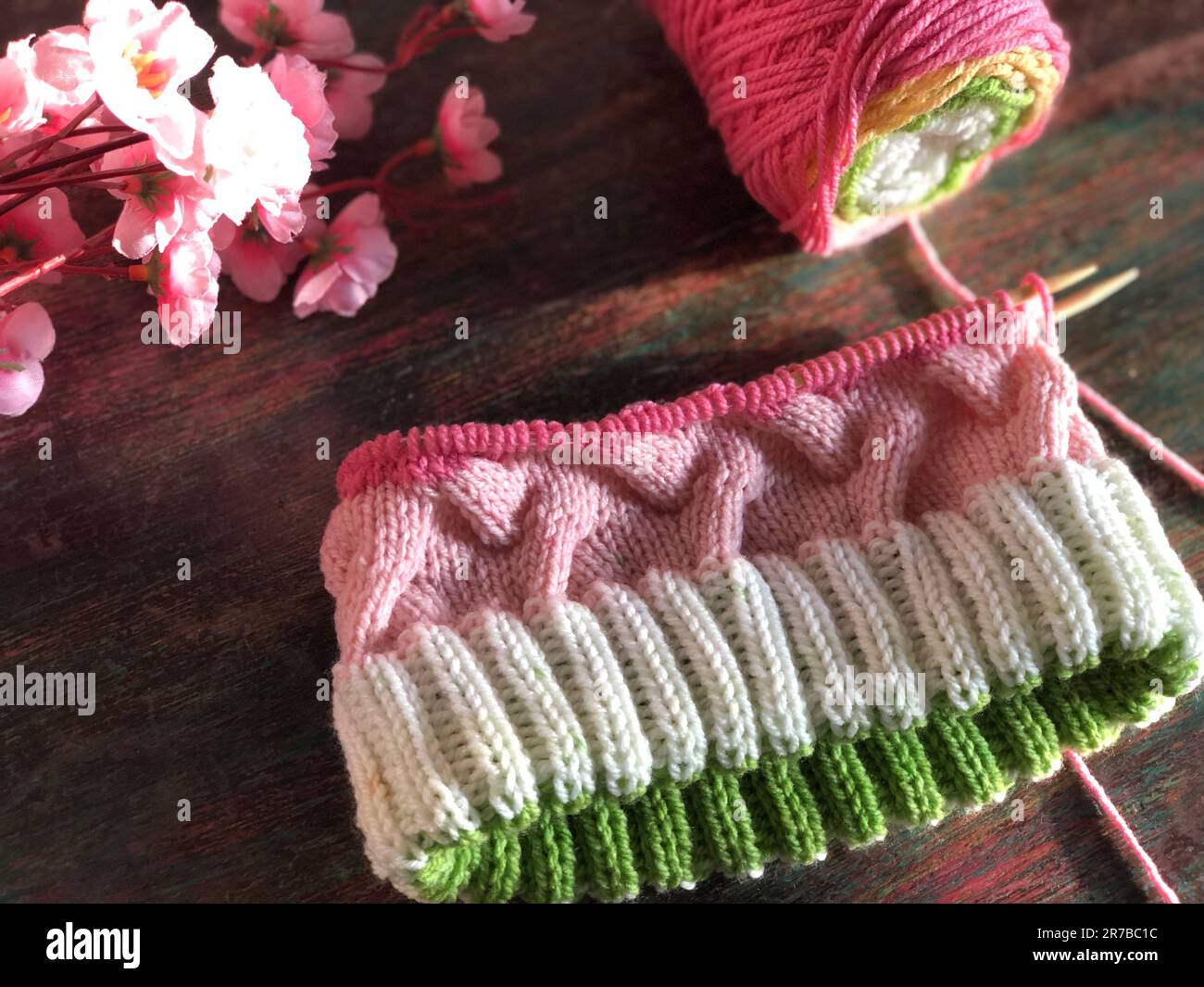 An up-close shot of a knitted item with strands of yarn draped over it ...