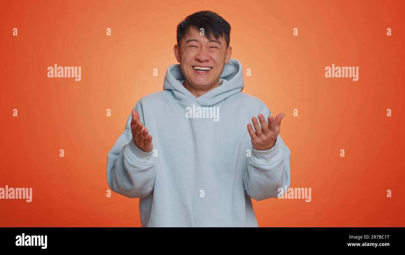 Amused asian man pointing finger to camera, laughing out loud, taunting ...