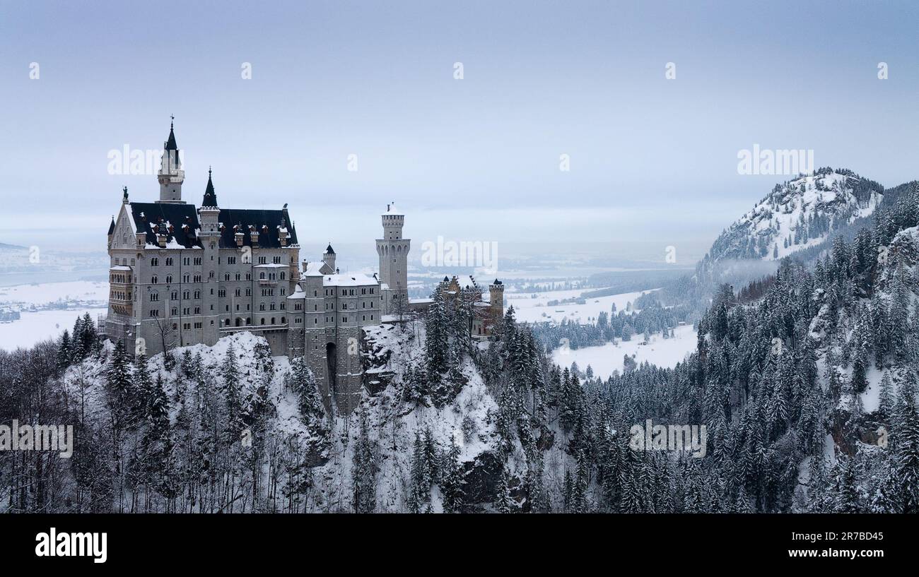 An aerial view of the historic Neuschwanstein castle on a snowy hill in ...