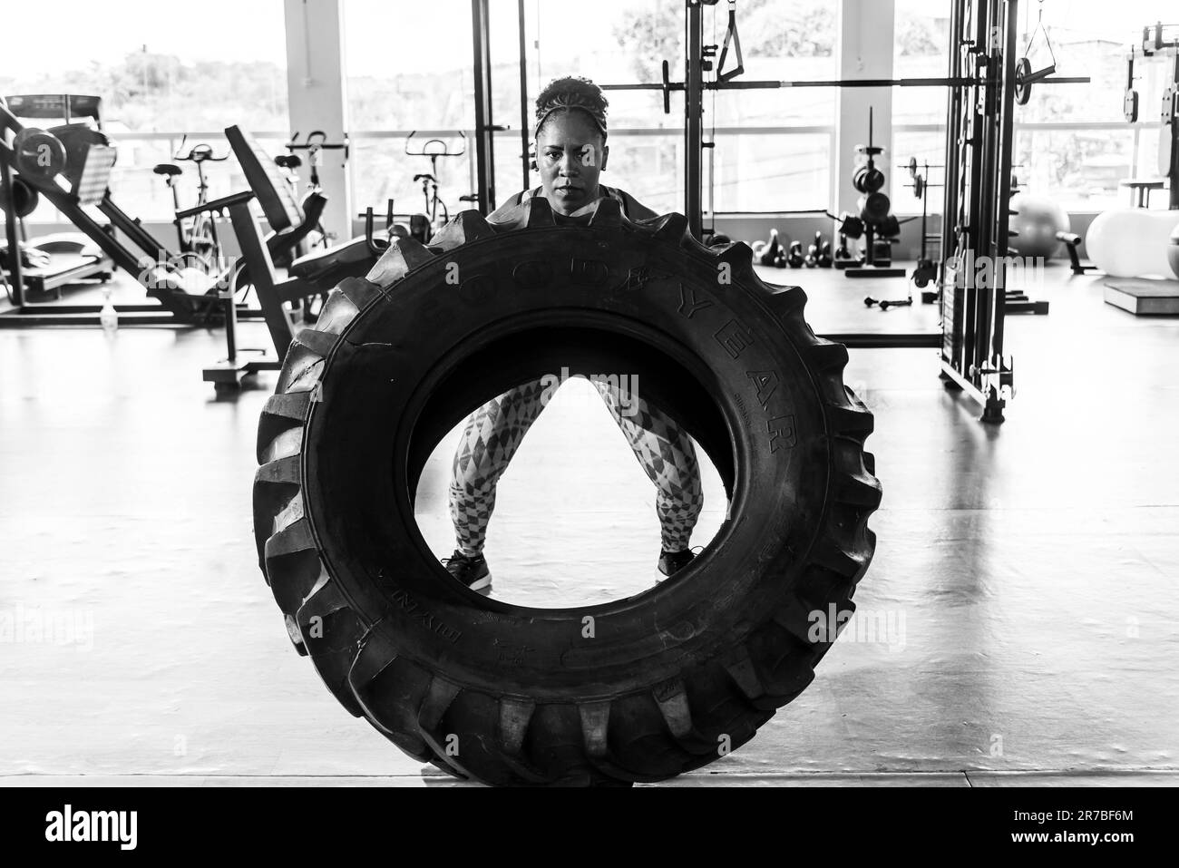 Athletic woman performing tire flipping exercise in gym setting ...