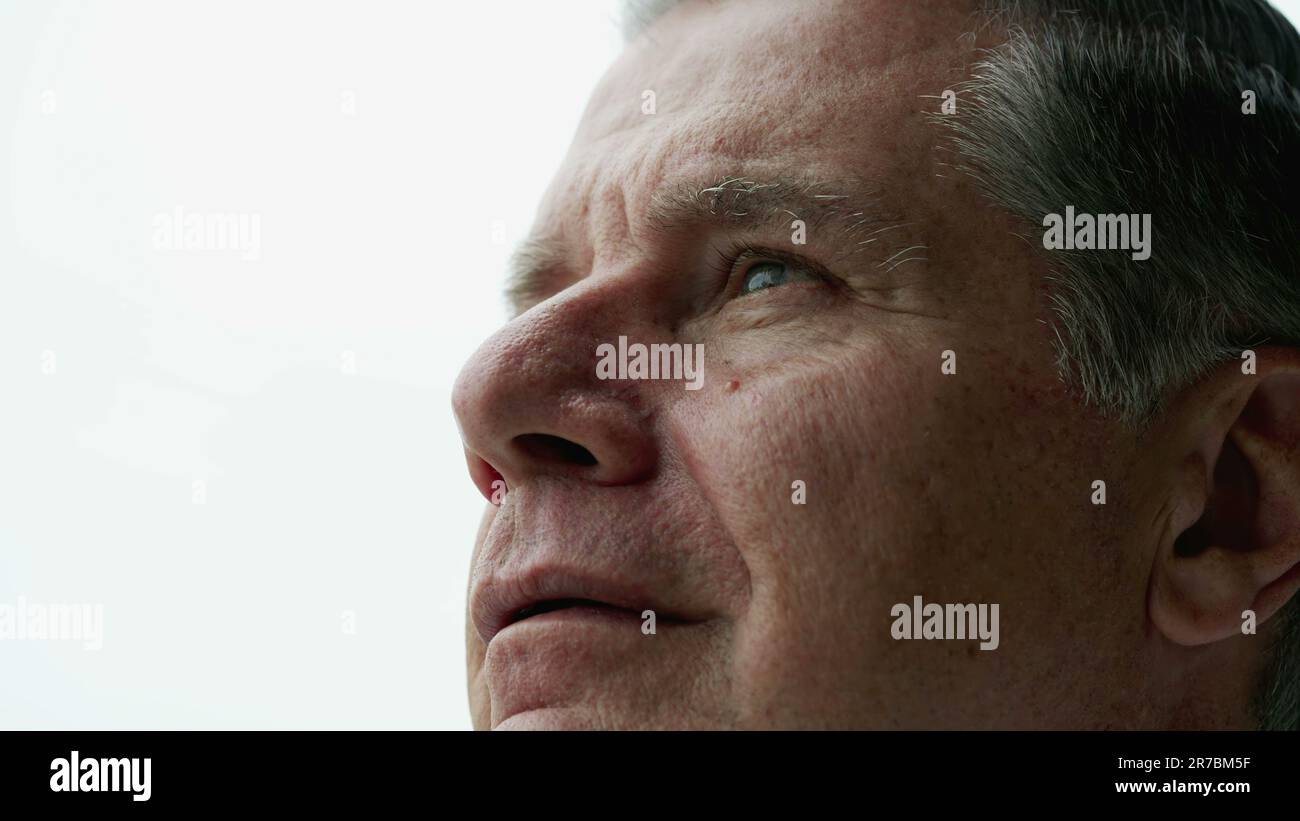 Contemplative older man close-up face looking up at sky with thoughtful ...