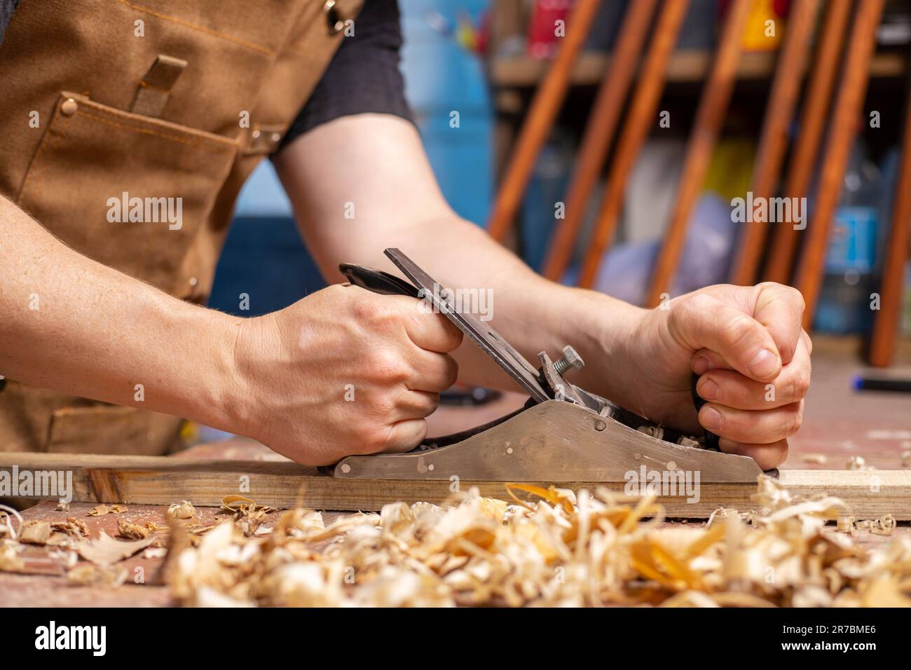 Carpenter's hands planing a plank of wood with a hand plane, workplace ...