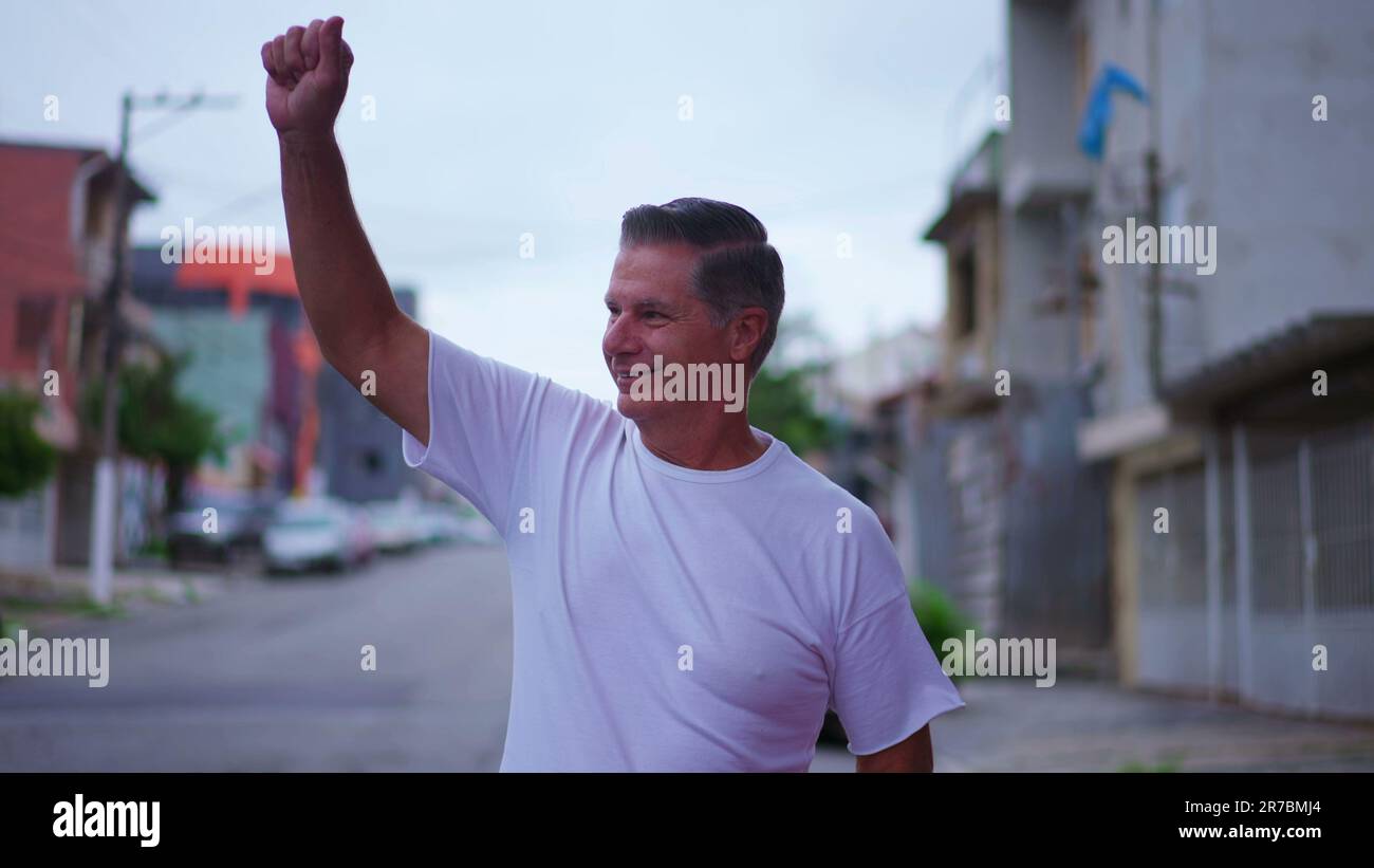 Happy older man waving hello to neighbors while walking in street. A ...
