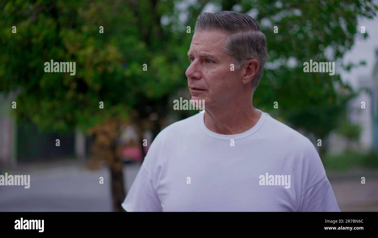 One contemplative senior man walking in city street observing urban ...