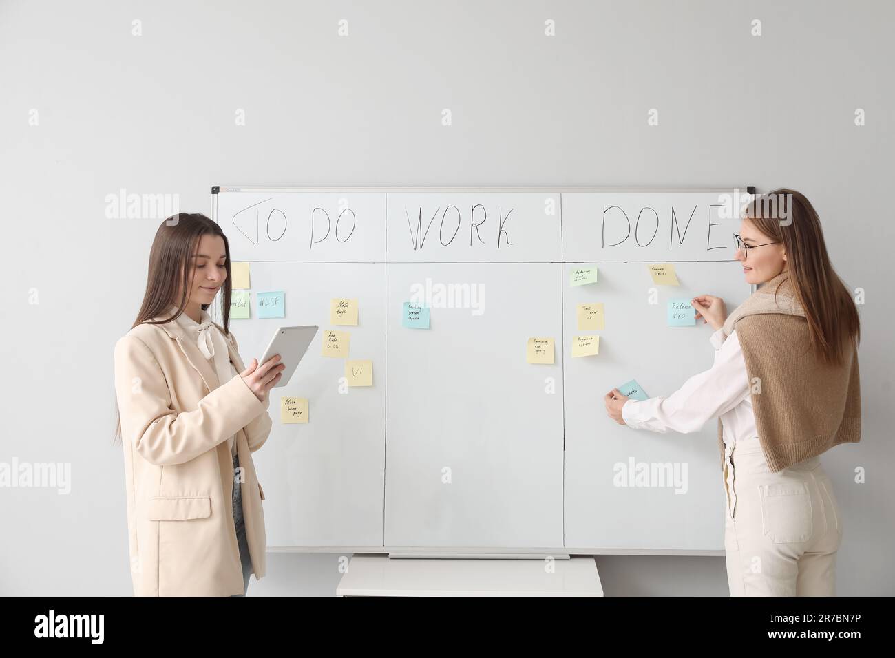 Young women working near scrum task board in office Stock Photo - Alamy