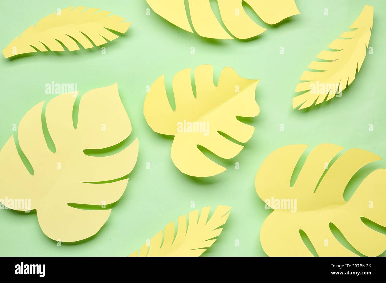 Yellow paper tropical leaves on green background Stock Photo - Alamy