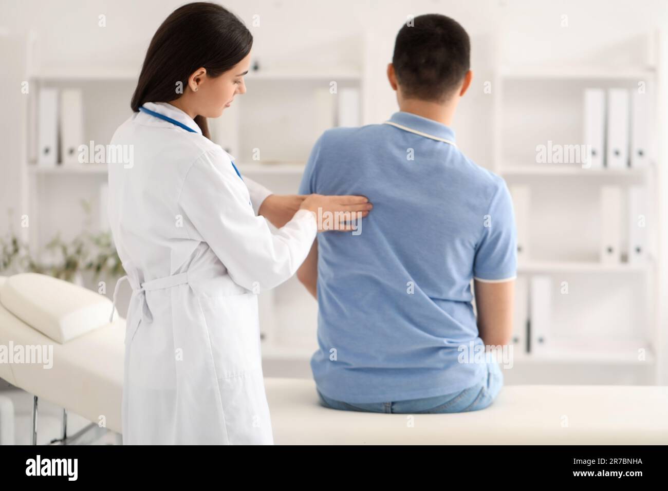 Female doctor checking posture of young man in clinic Stock Photo - Alamy