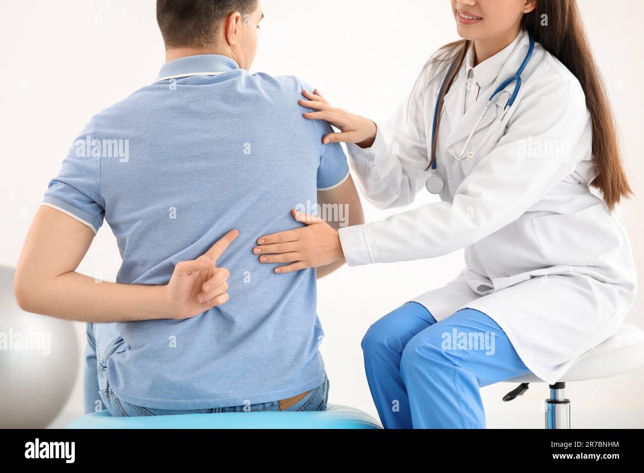 Female doctor checking posture of young man in clinic Stock Photo - Alamy