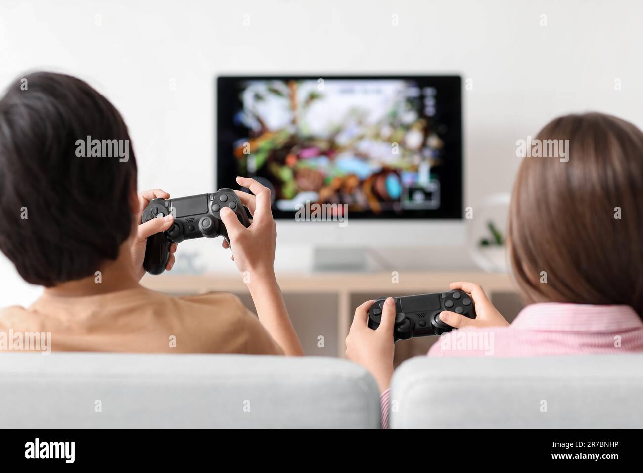 Little children playing video game at home, back view Stock Photo - Alamy