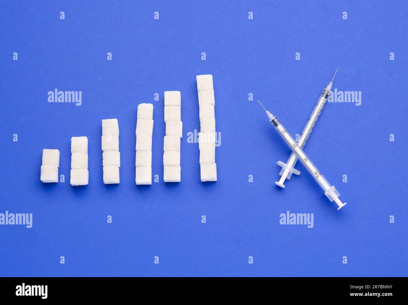 Sugar cubes with syringes for insulin injection on blue background ...