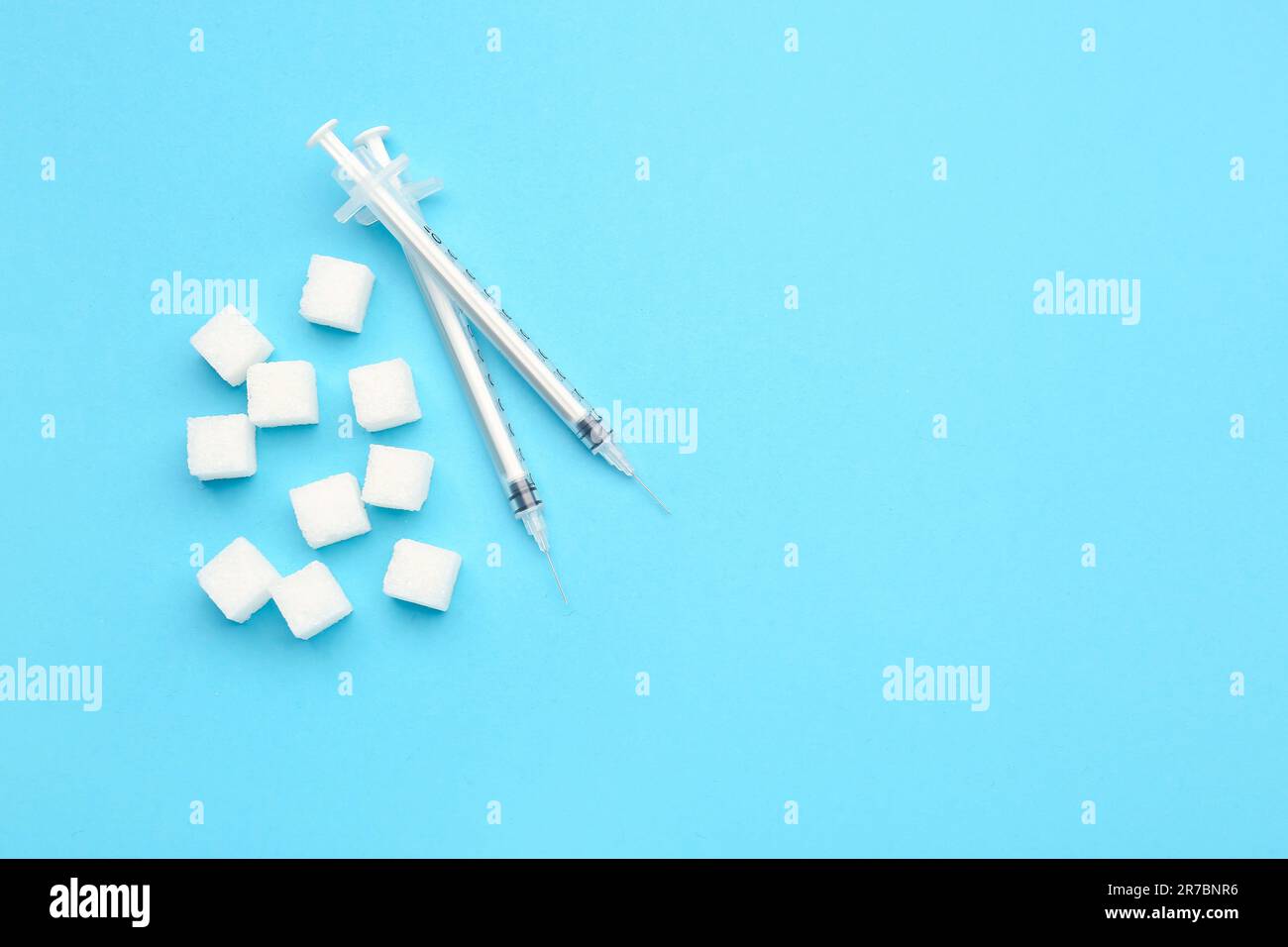 Sugar cubes with syringes for insulin injection on blue background ...