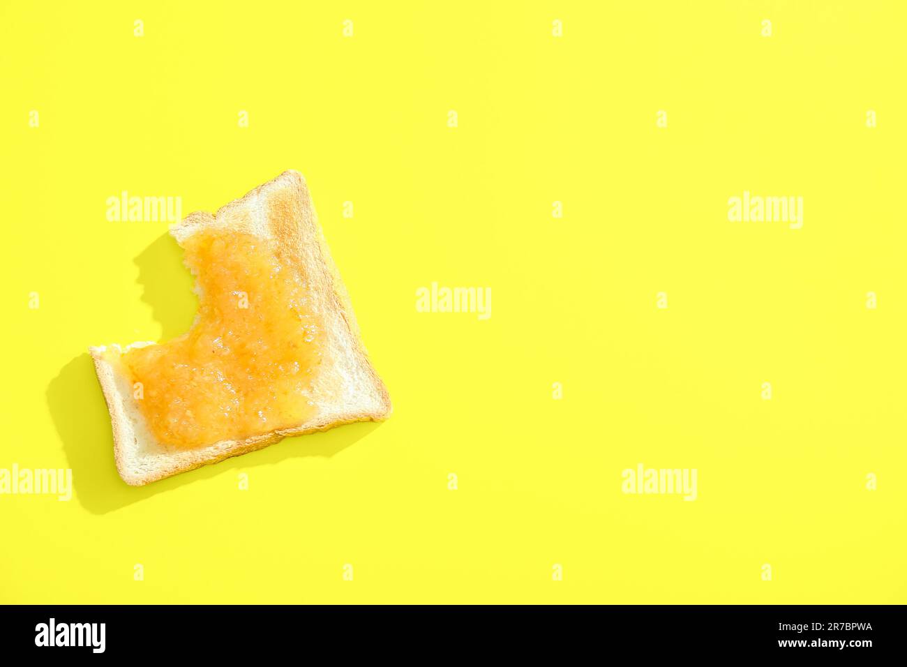 Bitten toast with sweet jam on yellow background Stock Photo - Alamy