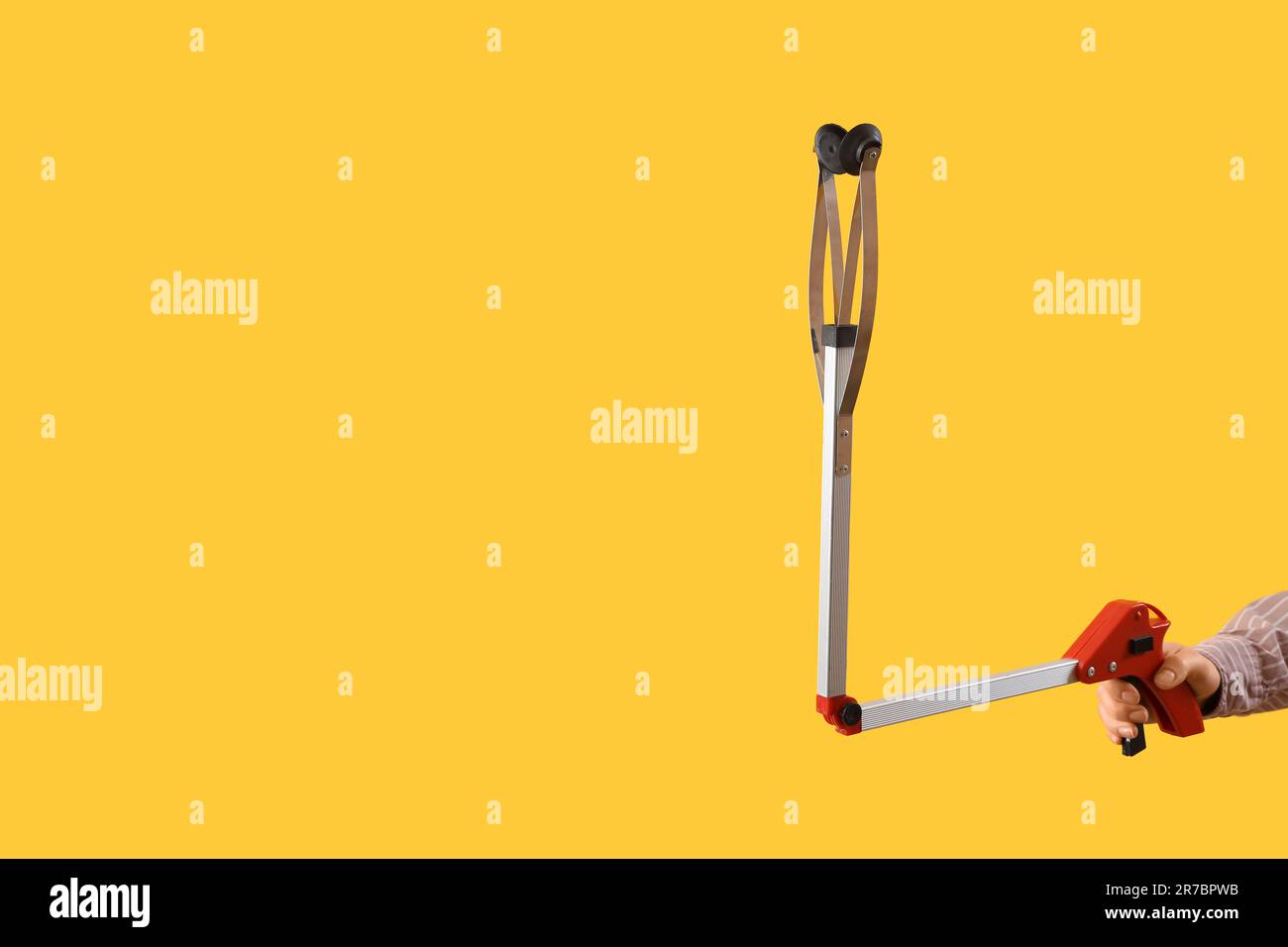 Female hand holding long reach grabber tool on yellow background Stock ...