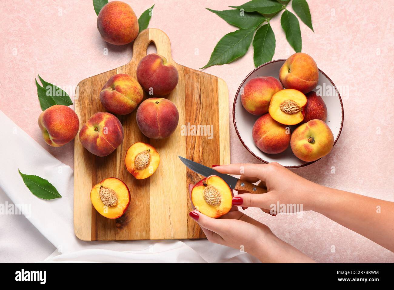 Woman cutting sweet peach on pink background Stock Photo - Alamy