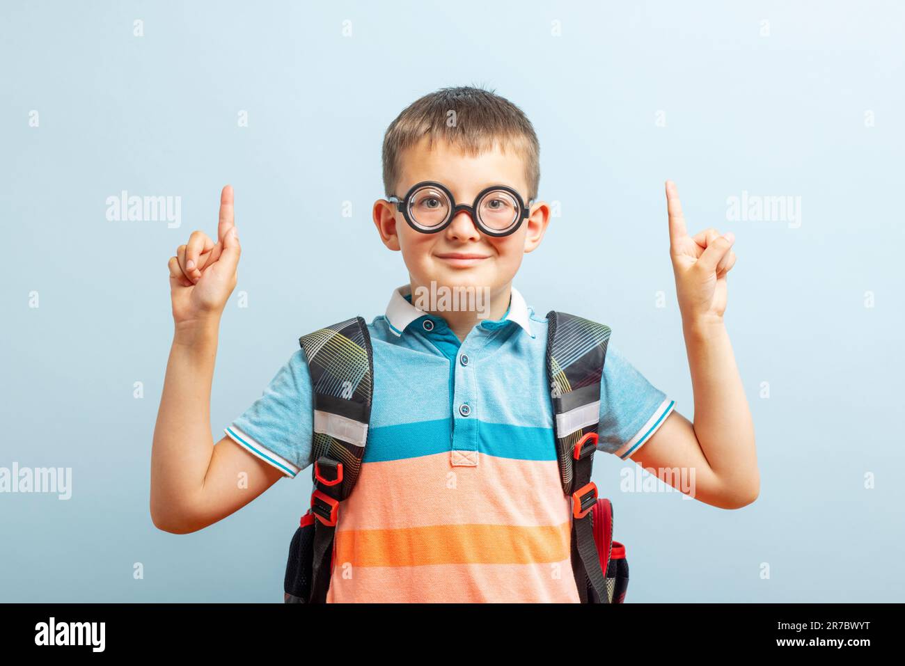 Happy school boy pointing fingers up showing something on blue ...
