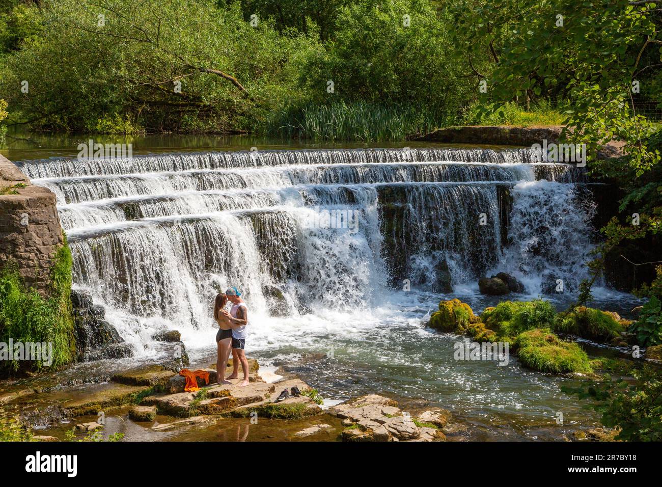 Young Couple embraced and kissing under a cascading waterfall on the ...