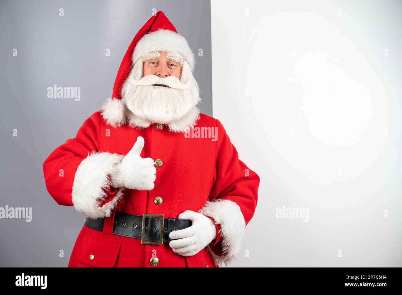 Santa claus peeks out from behind an empty Christmas advertisement and ...