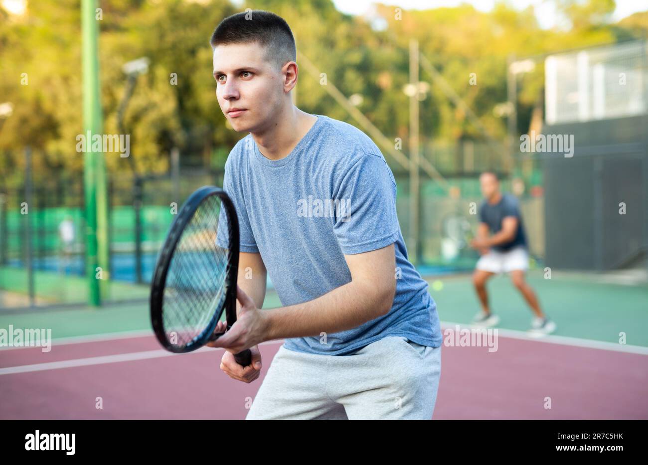 Young man playing tennis on court Stock Photo - Alamy